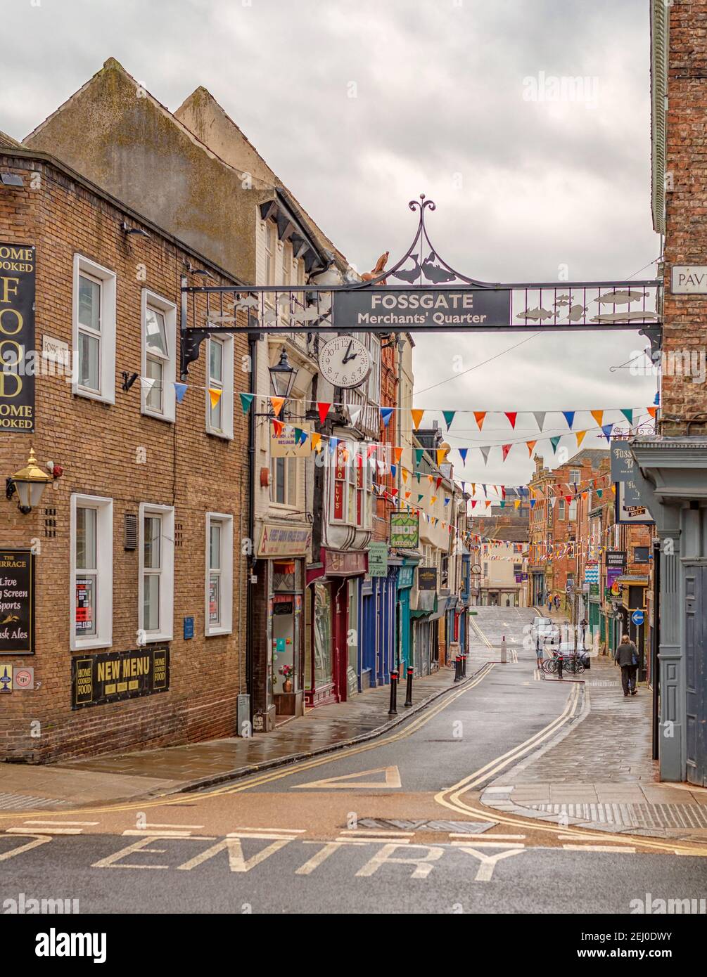 A street festooned with colourful bunting. Shops and restaurants are on ...