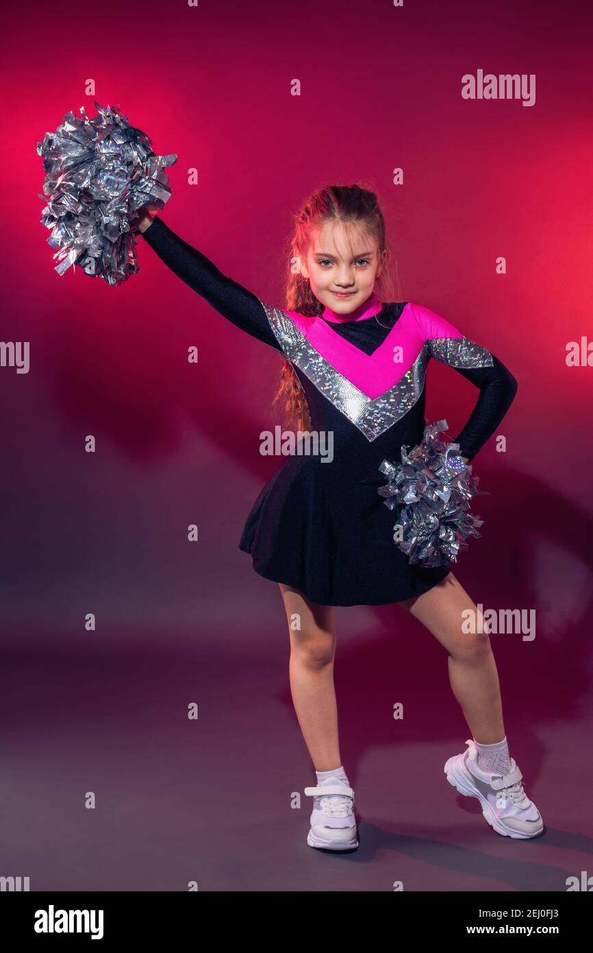 Little cheerleader practicing dance elements in studio with color light ...