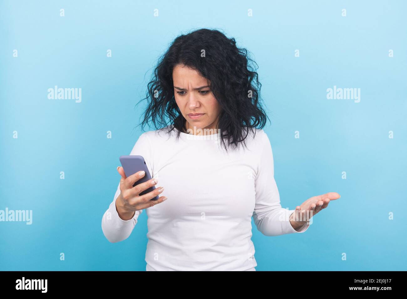 brunette girl is confused looking at her cell phone screen Stock Photo ...