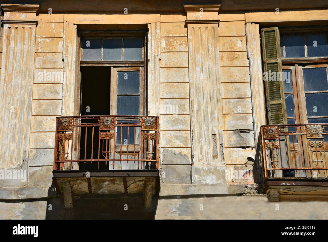 Neoclassical house facade with weathered wooden windows, rusty iron ...