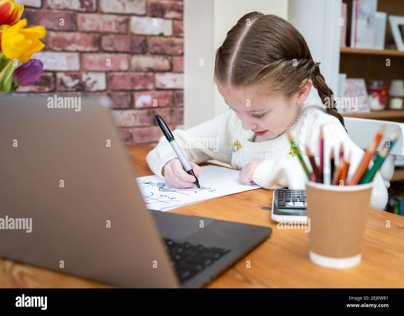 Cute pretty young girl doing complex maths writing calculations at home ...