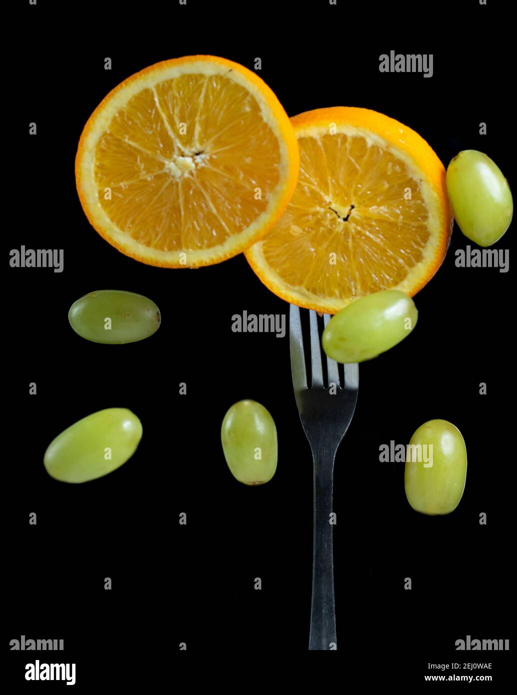 Slices of orange and grapes on a black background. Healthy eating ...