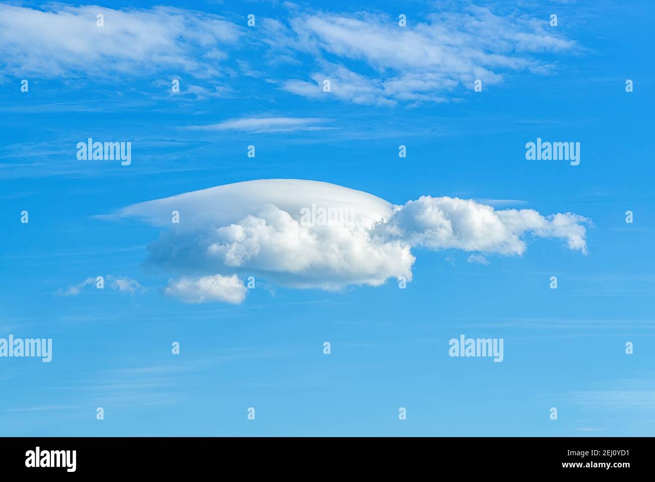 Small lenticular cloud against translucent cirrus clouds high in a ...