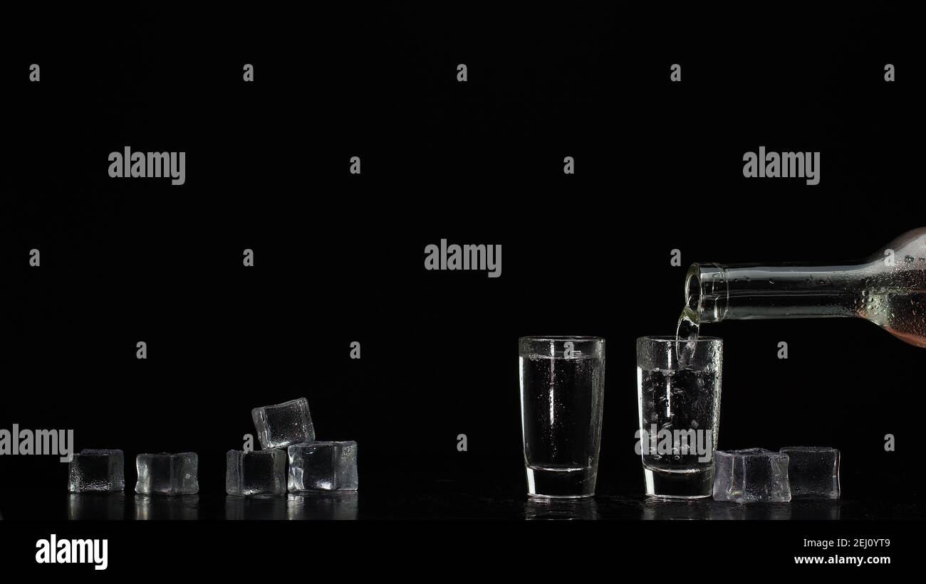 Two hands with glasses of vodka making cheers on black background with ...