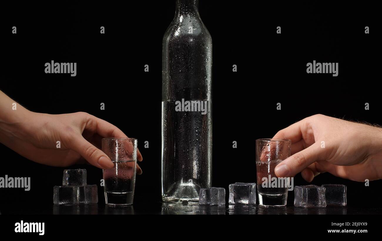 Bartender pouring up two shots of vodka with ice cubes from a bottle ...