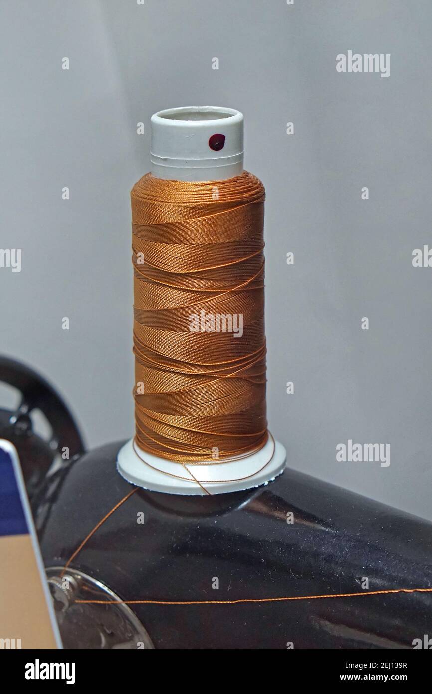Golden thread bobbin at old sewing machine Stock Photo - Alamy