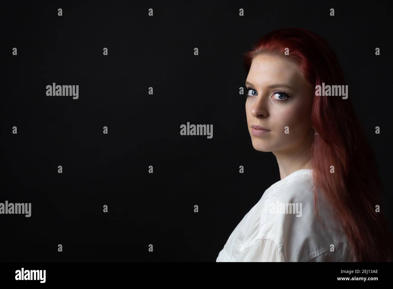 Low key portrait of beautiful young woman turning back to camera ...