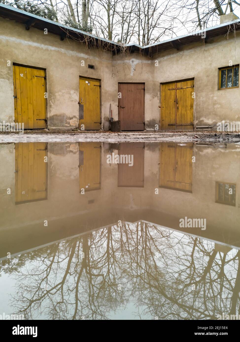 Small building with few doors reflected in small puddle Stock Photo - Alamy