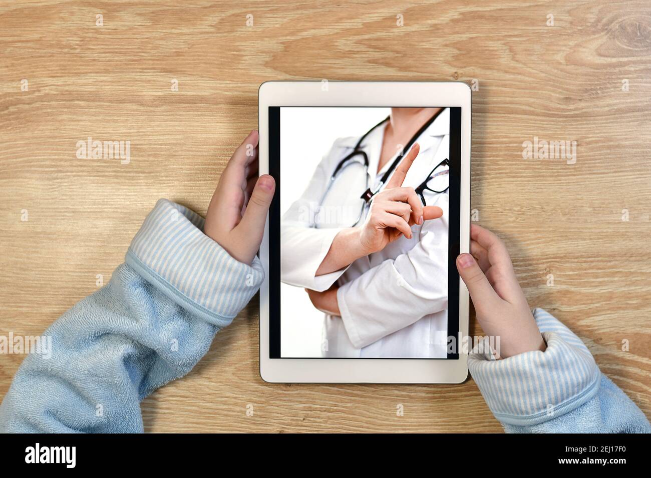 Remote online telemedicine. A child in home clothes with a tablet in ...