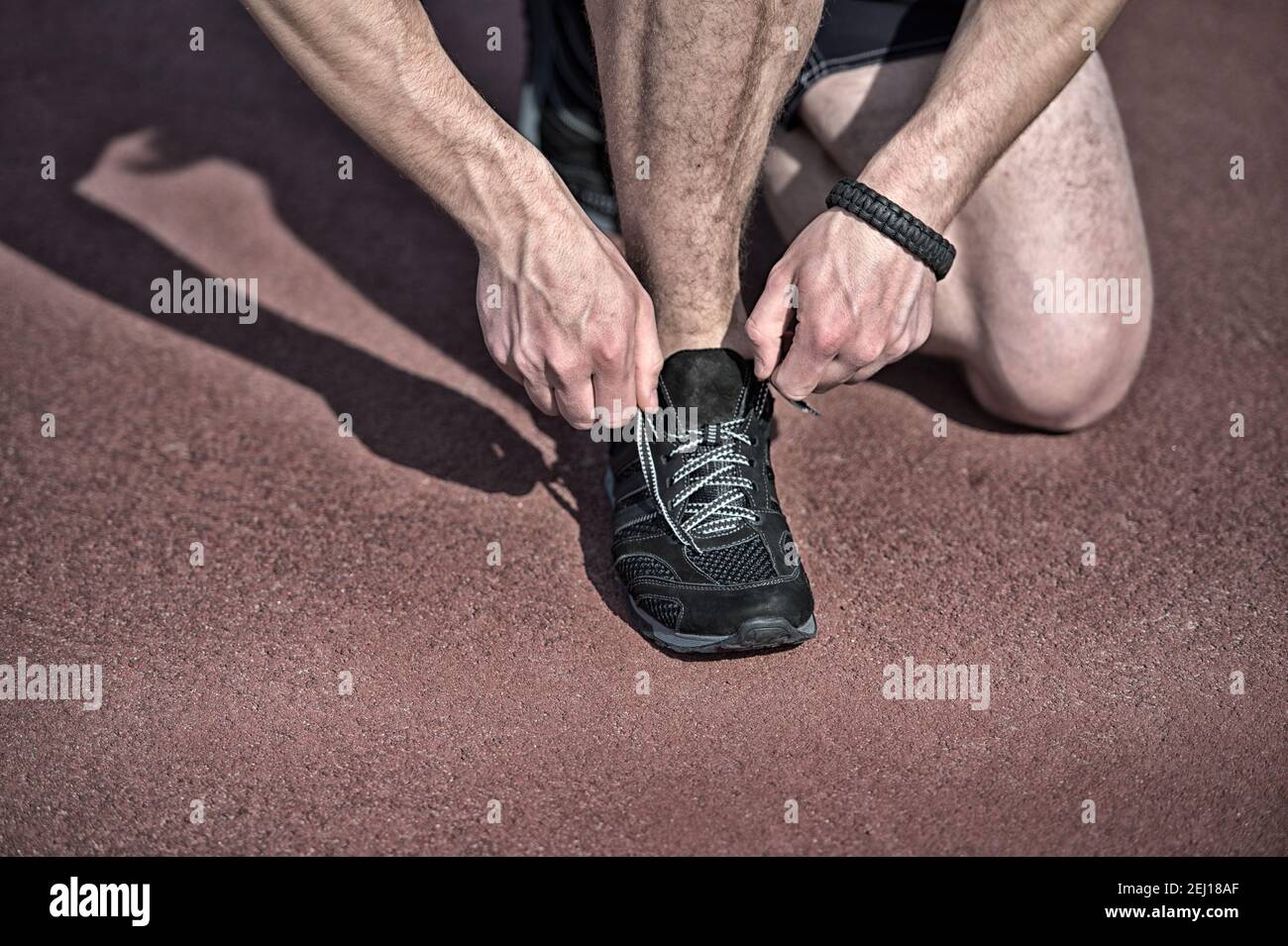 runner, man tie shoe laces on running track sunny outdoor in sportswear ...