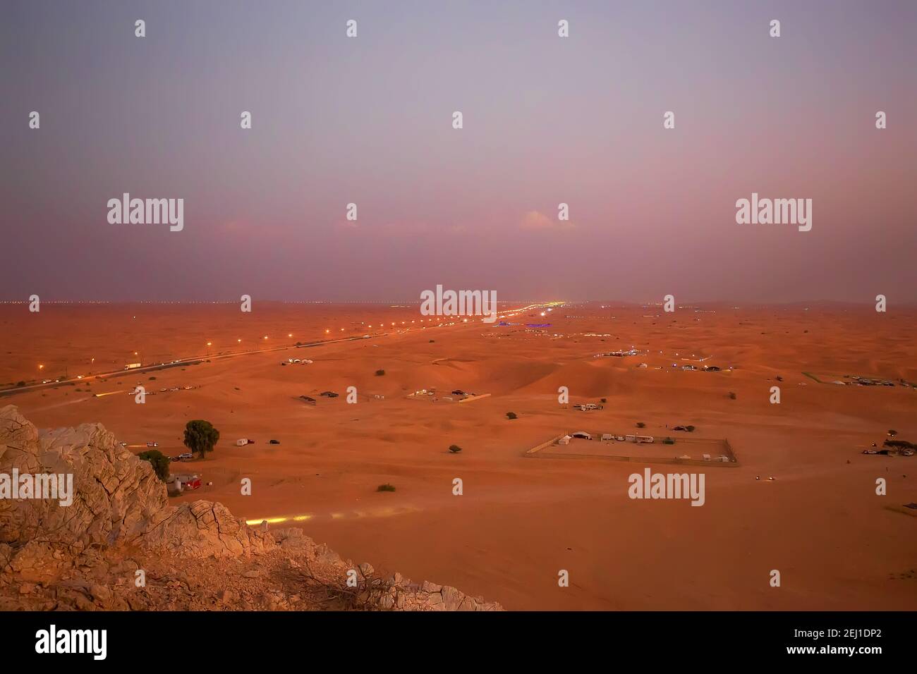 Evening dusk at Al Awir Dubai desert with road, lights, camps, orange ...