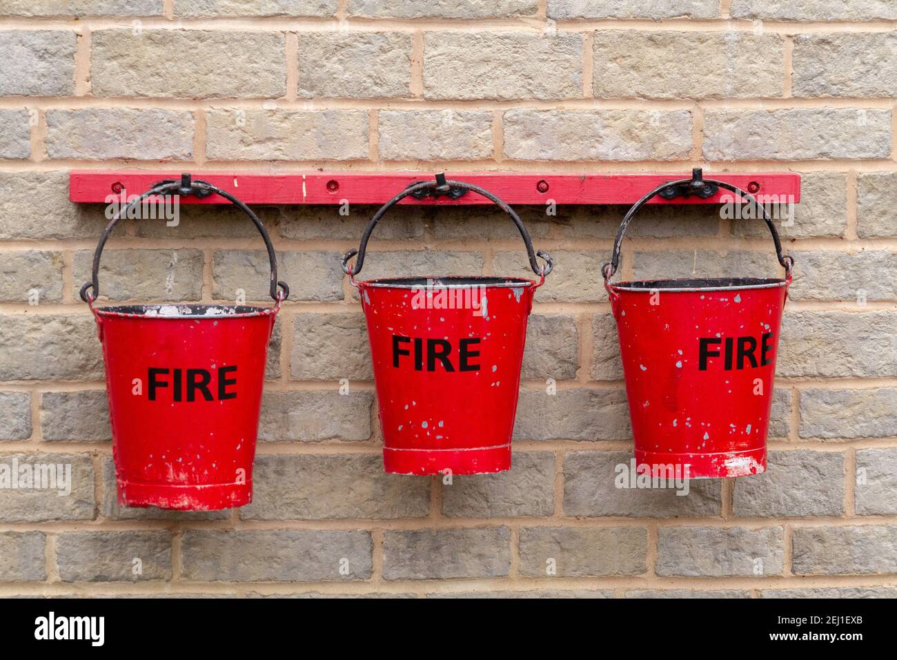 Three red fire buckets hanging on a wall Stock Photo - Alamy