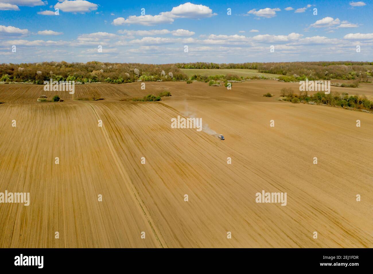 Aerial view large tractor cultivating a dry field. Top down aerial view ...