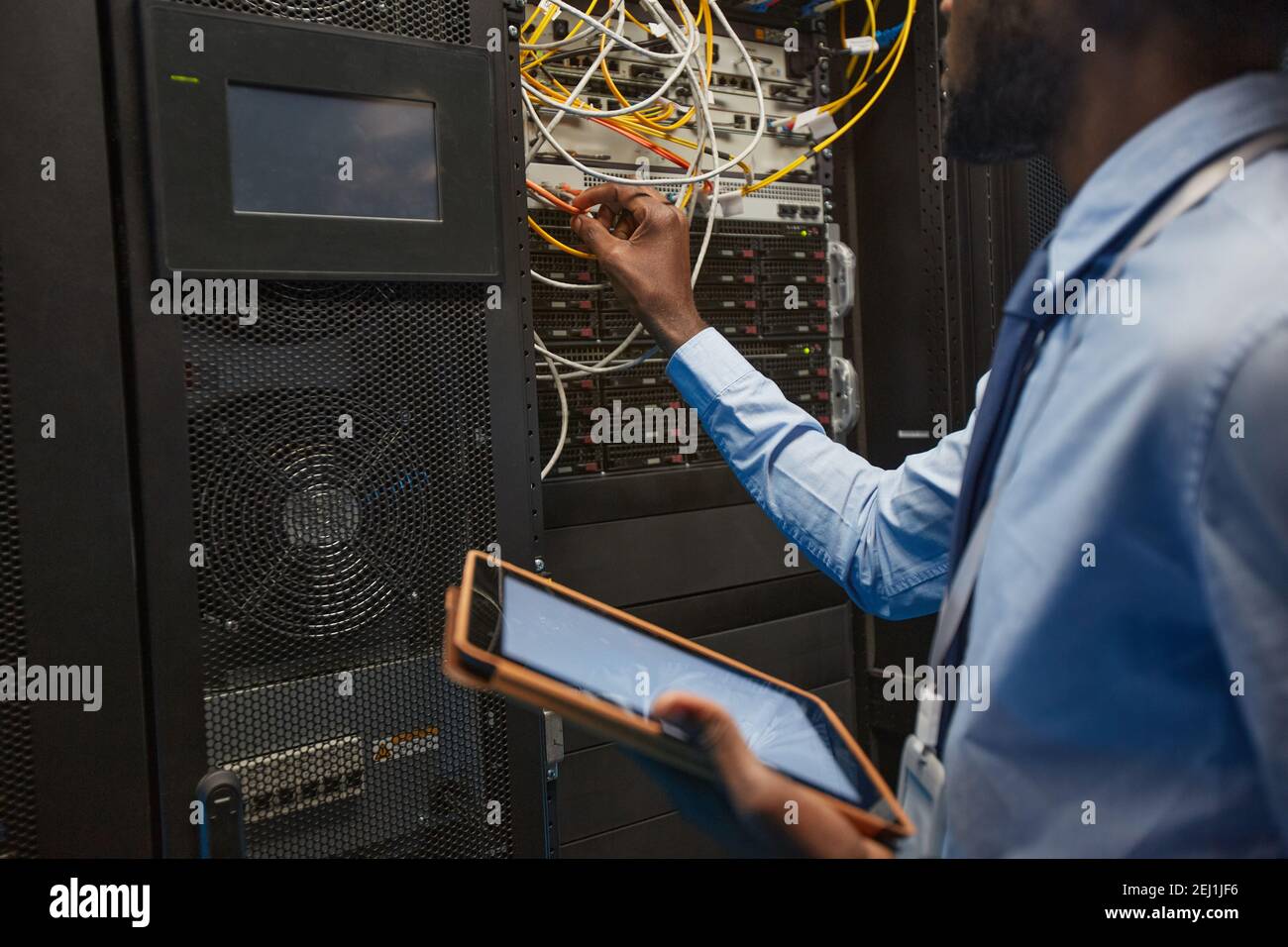Cropper portrait of African American network engineer connecting cables ...