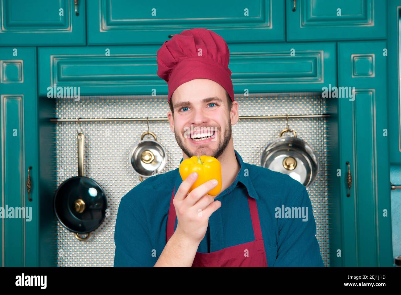 Guy in chef hat smile with yellow pepper vegetable in kitchen ...