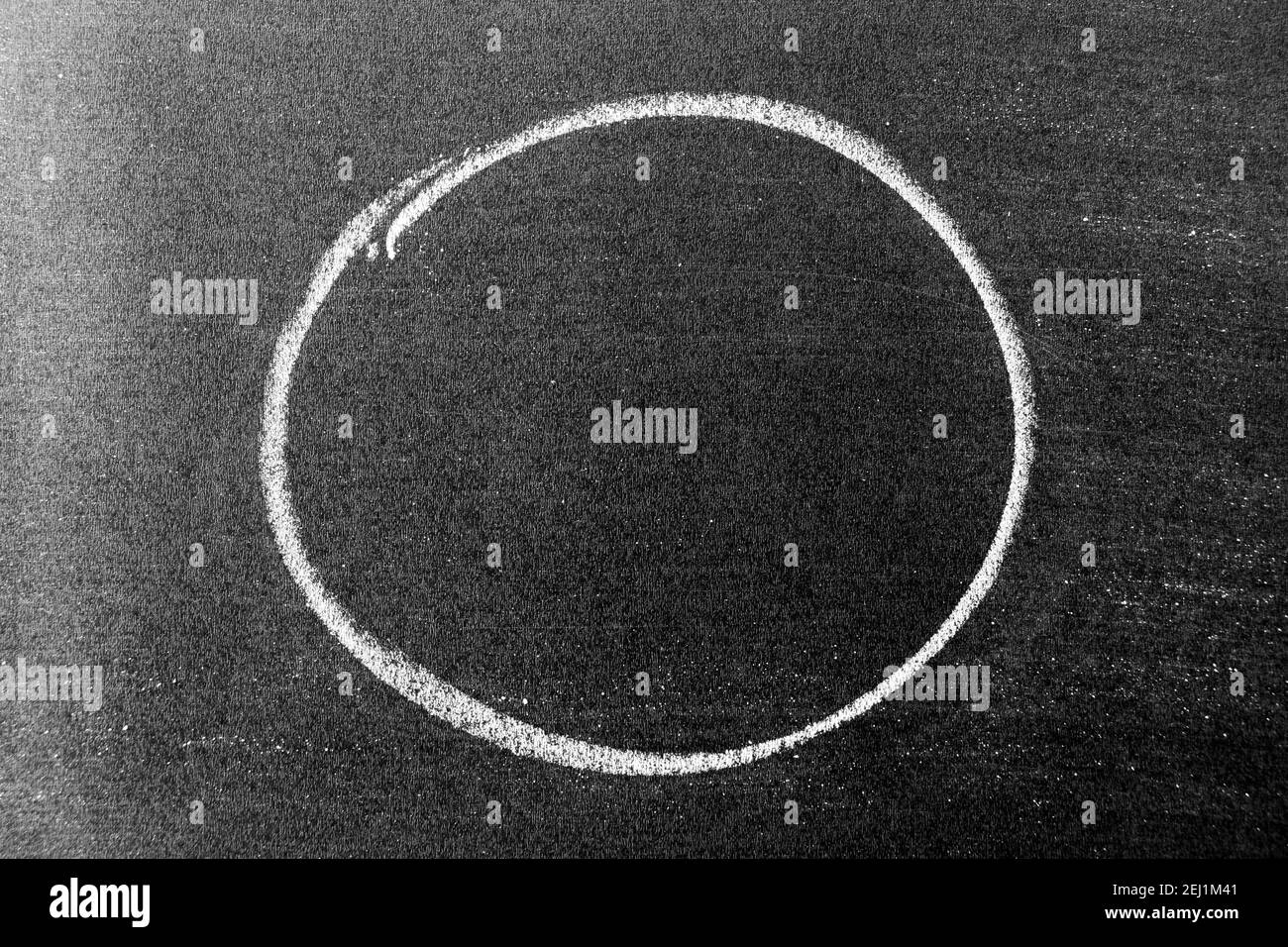 White color chalk hand drawing in circle or oval shape on black board ...
