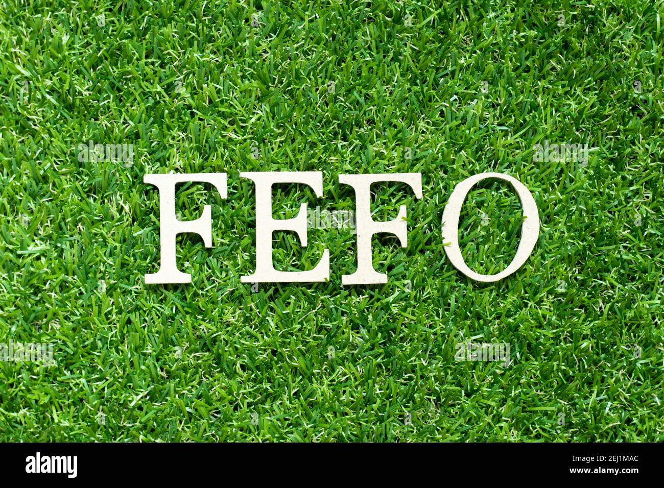 Alphabet letter in word FEFO (first expired first out) on green grass ...