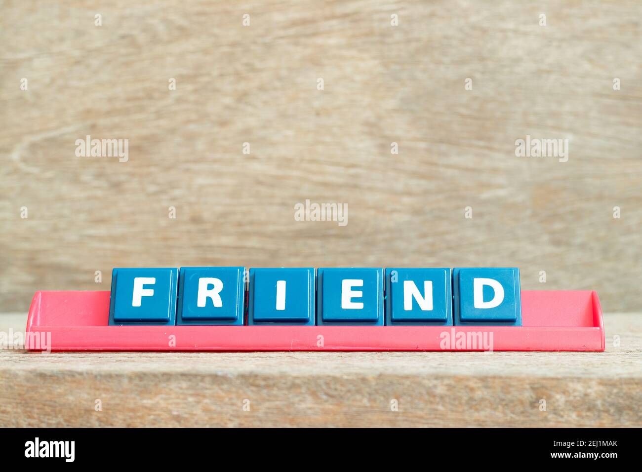 Tile alphabet letter with word friend in red color rack on wood ...