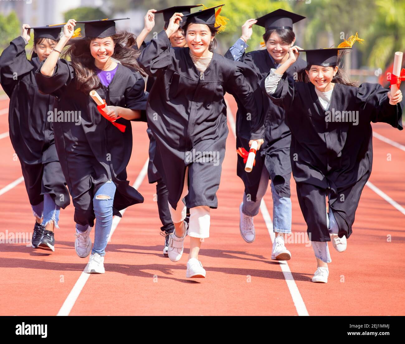 happy graduation students holding diploma and running on the stadium at ...