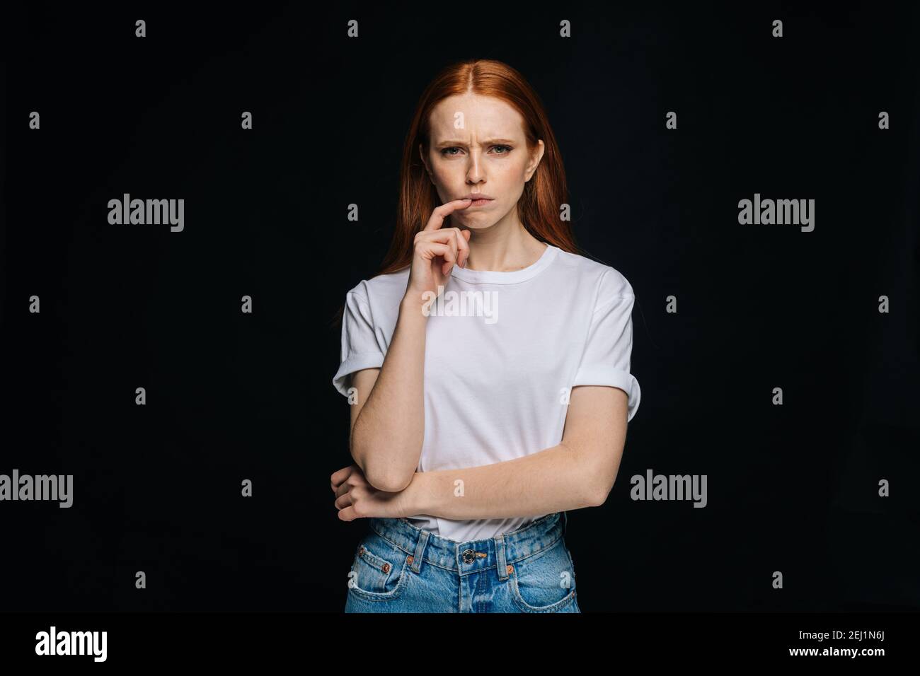Thinking young woman in T-shirt and denim pants thinking about question ...