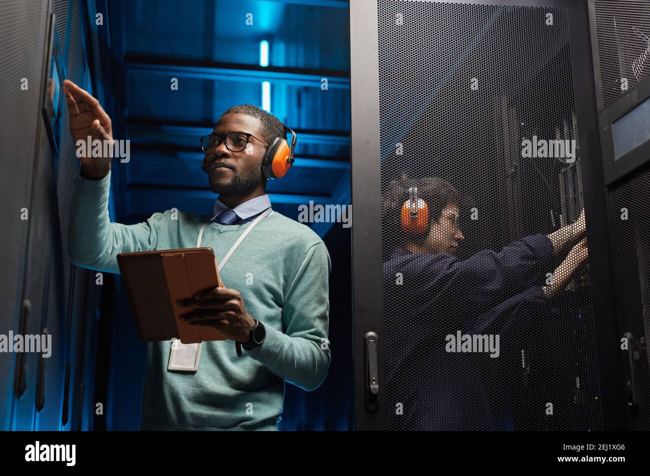 Waist up portrait of two technicians setting up computer network while ...