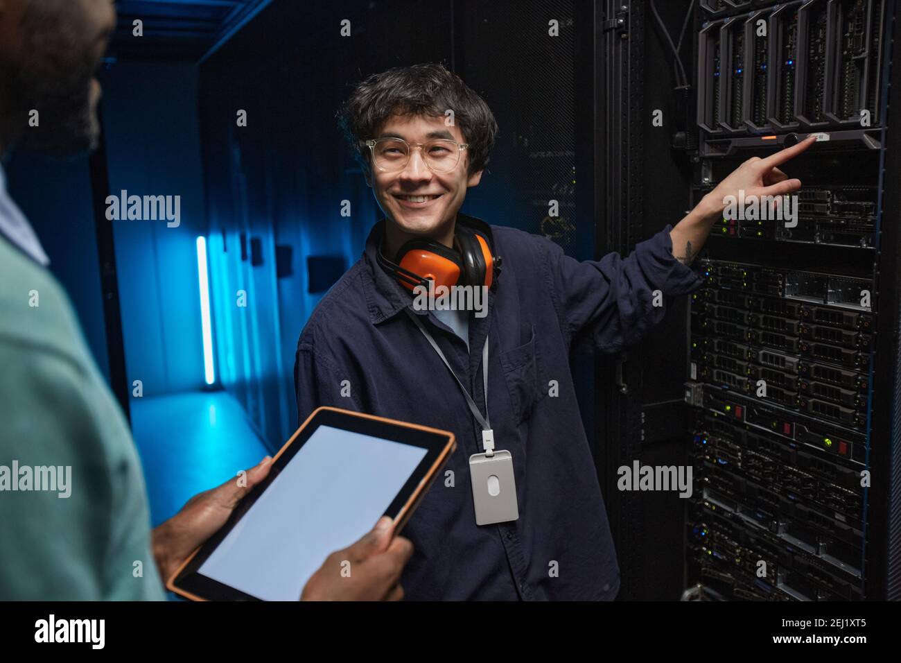Waist up portrait of smiling Asian man looking at colleague while ...