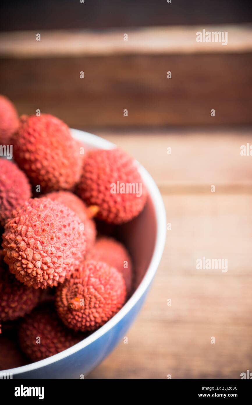 Red ripe lychees on the rustic background. Selective focus. Shallow ...