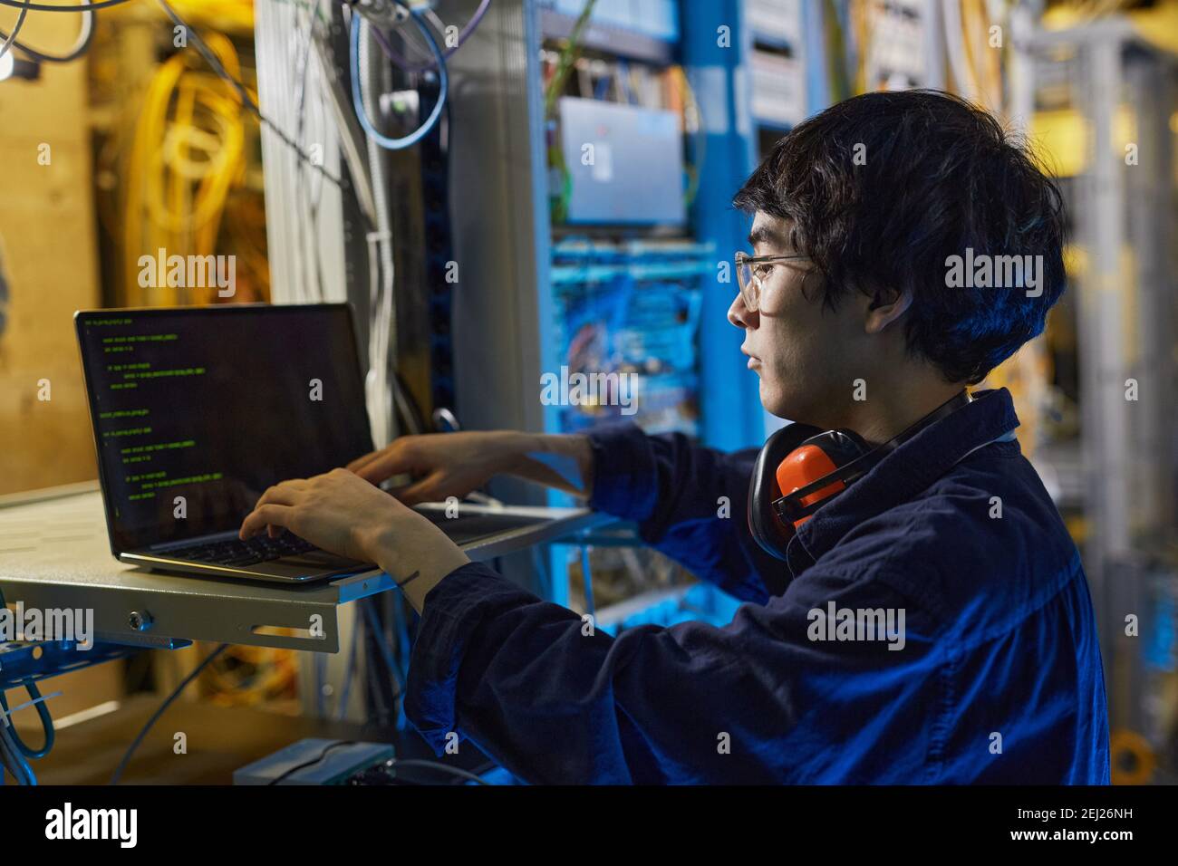 Side view portrait of young network technician using laptop while ...