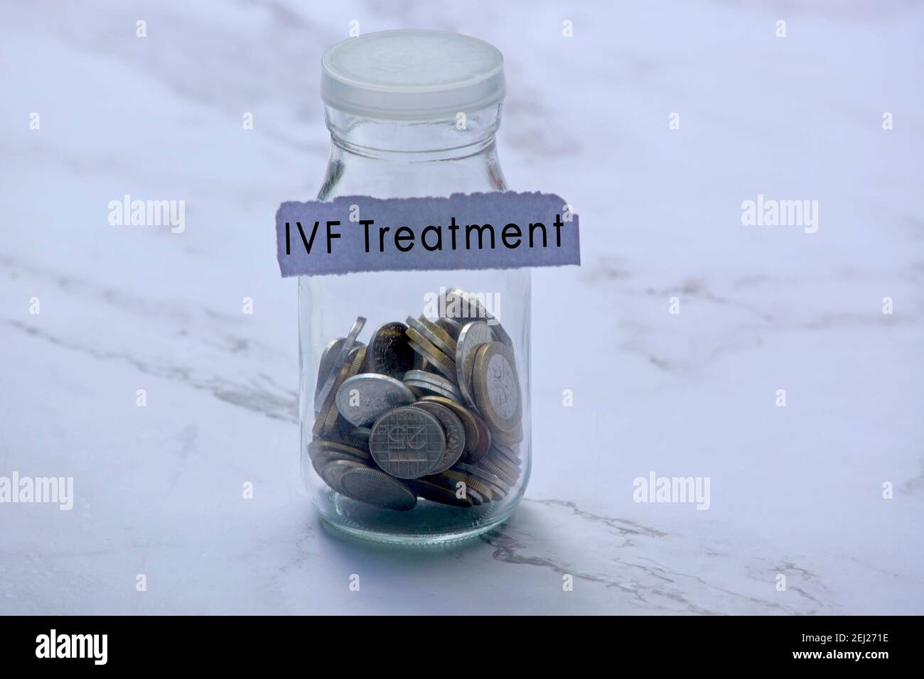 Glass jar with multicurrency coins and text on white torn paper - IVF ...