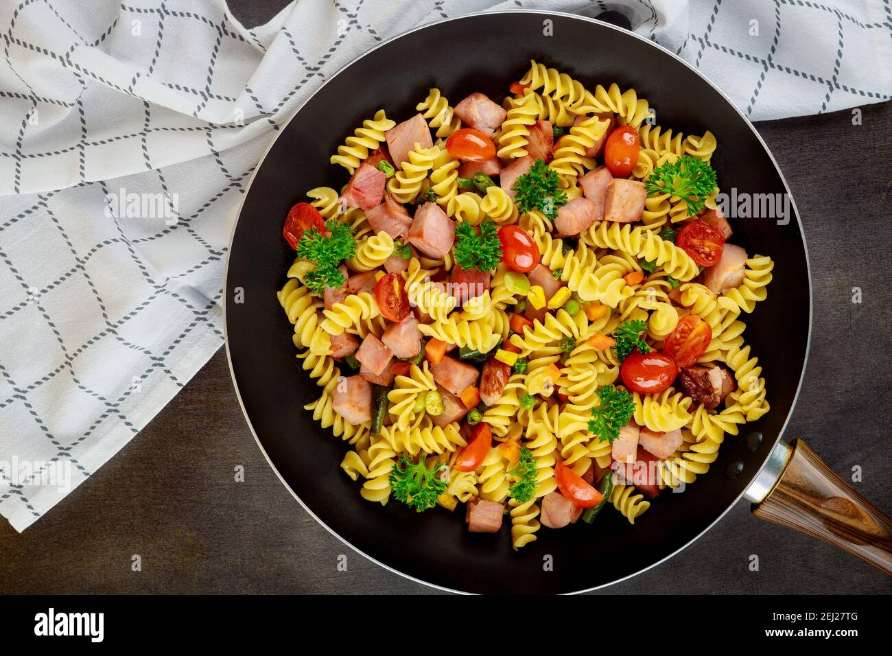 Colorful pasta rotini, cherry tomatoes and ham on pan. Close up. Top ...