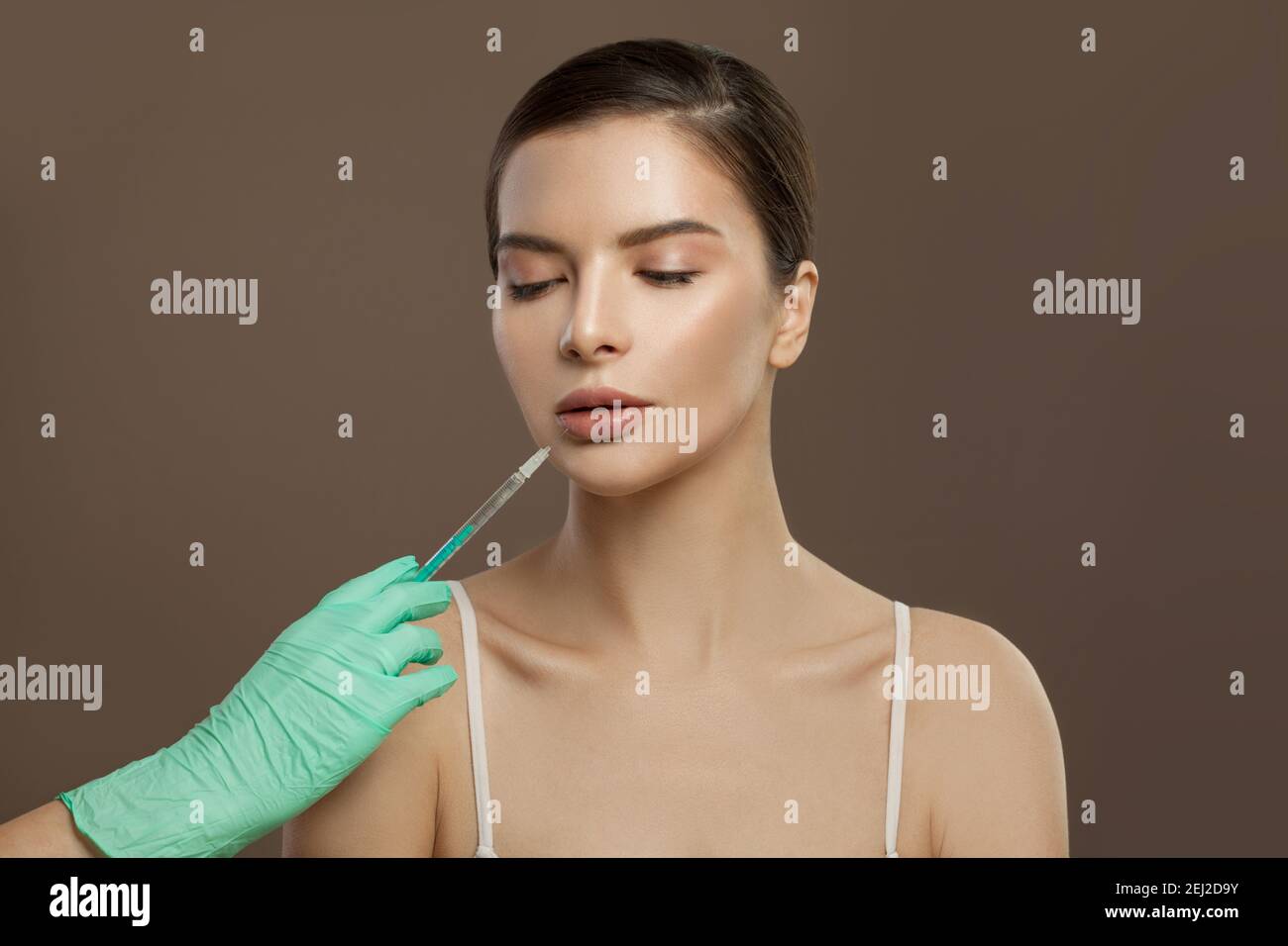 Pretty female face with syringe near lips. Lip augmentation and ...