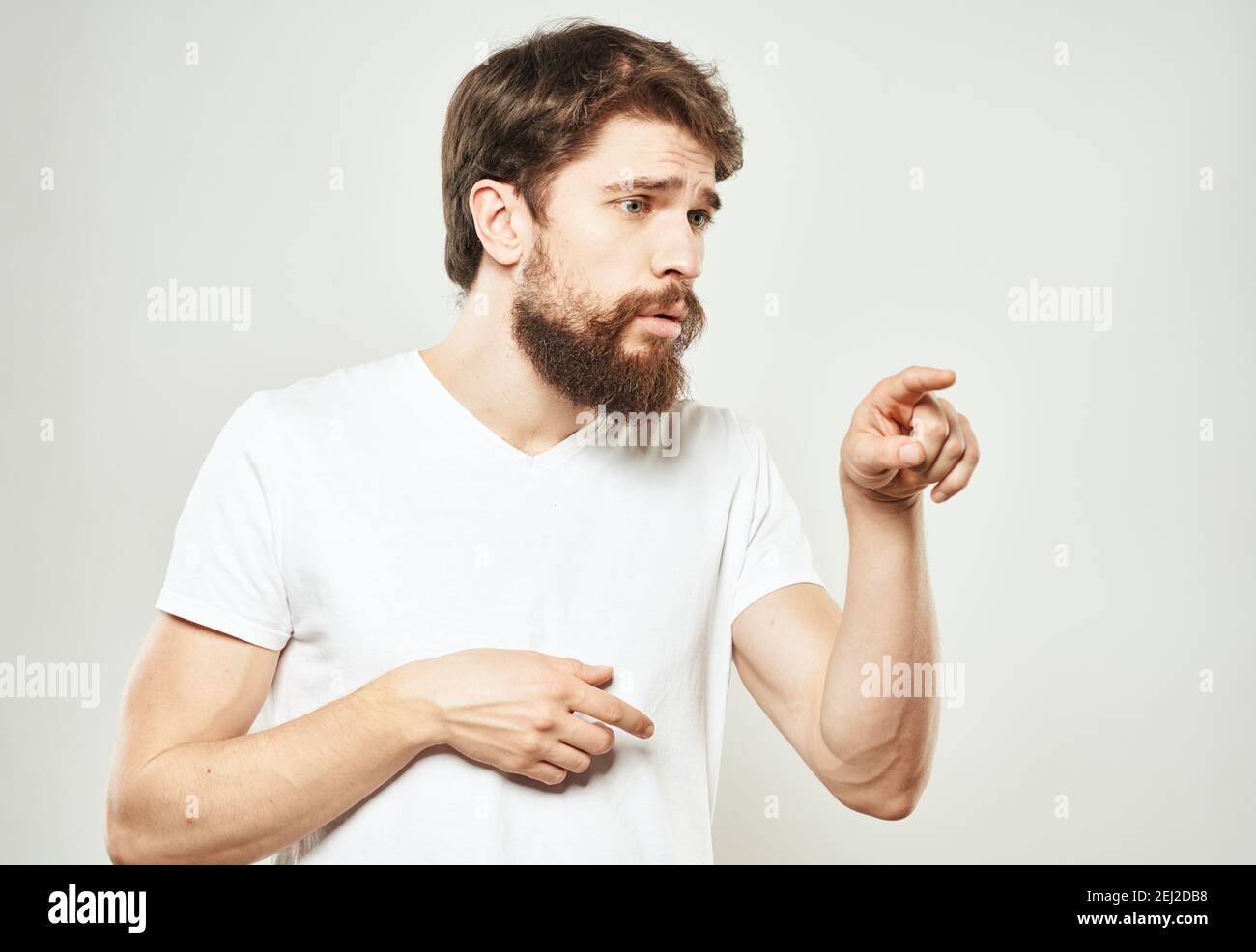 Guy in a white T-shirt on a light background emotions sad face cropped ...