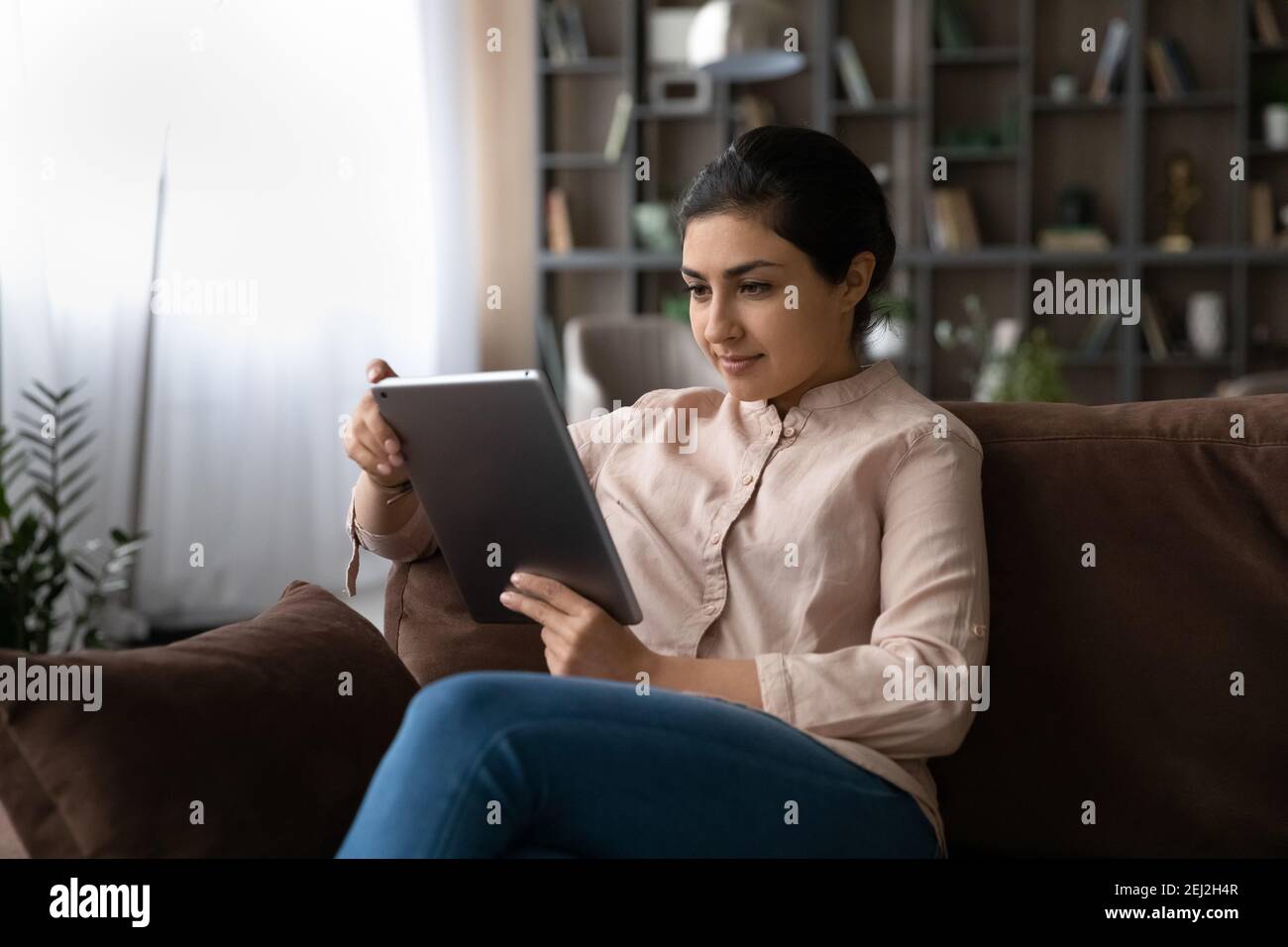 Young Indian woman relax on sofa using tablet Stock Photo - Alamy