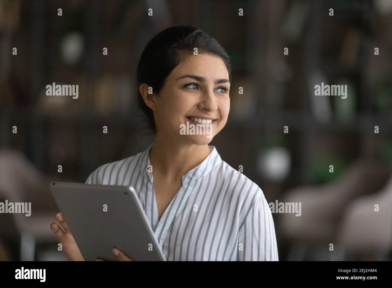 Smiling Indian woman use tablet dreaming thinking Stock Photo - Alamy
