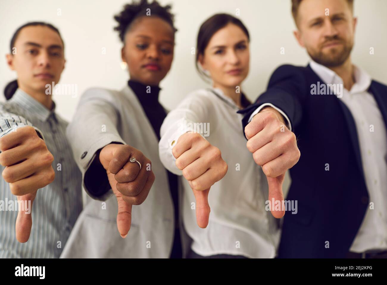 Group of young business people giving thumbs down to show their dislike ...