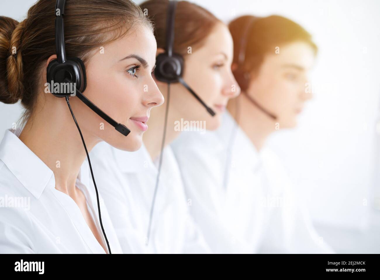 Call center. Beautiful young woman using headset and computer to help ...