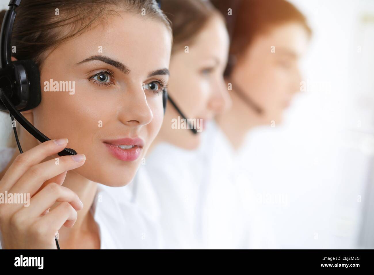 Call center. Beautiful young woman using headset and computer to help ...