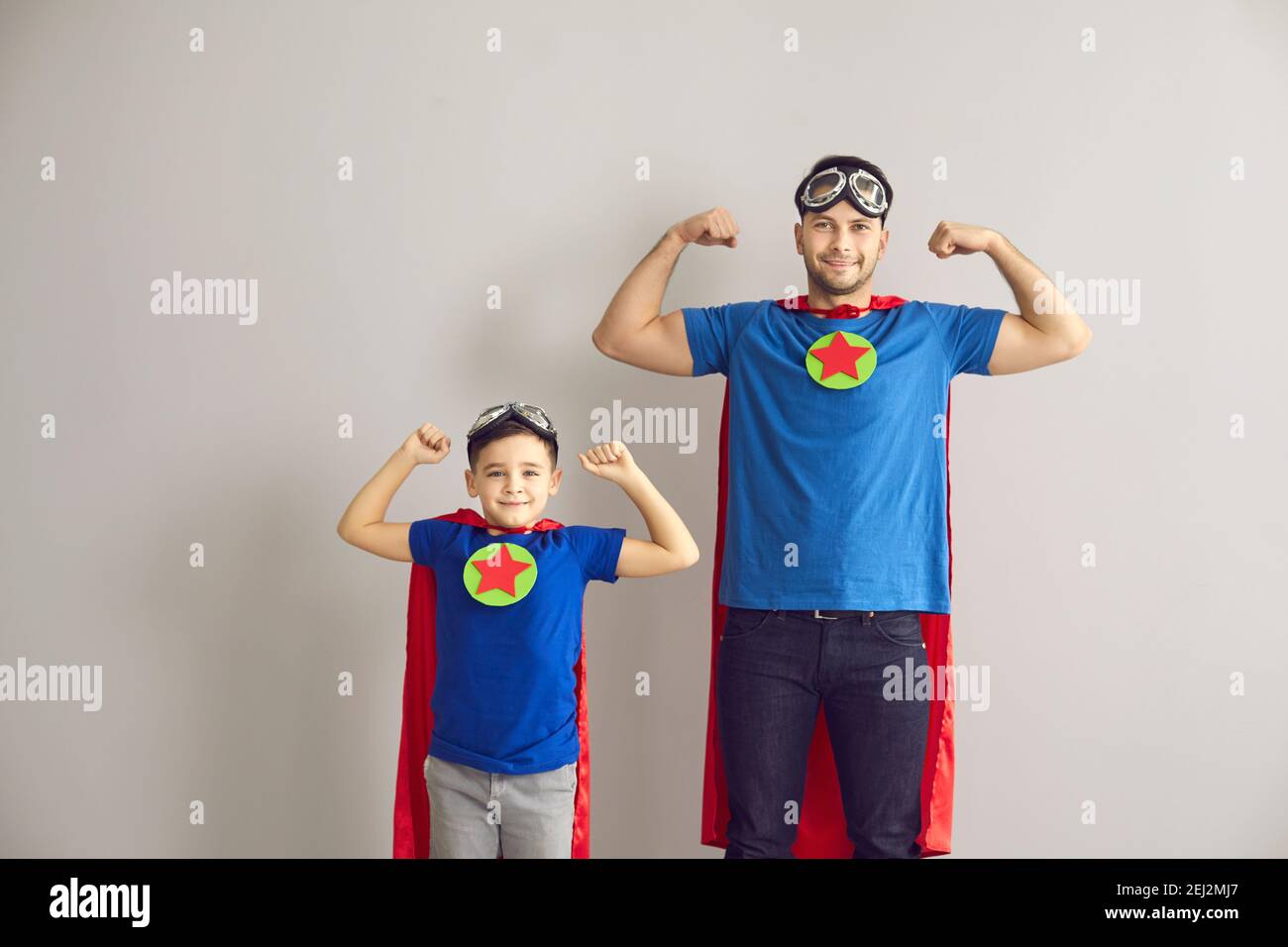 Powerful father with son in superhero costume showing muscles at camera ...