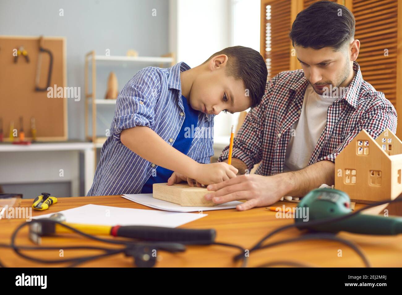 Little boy and his father making wooden house models as part of school ...