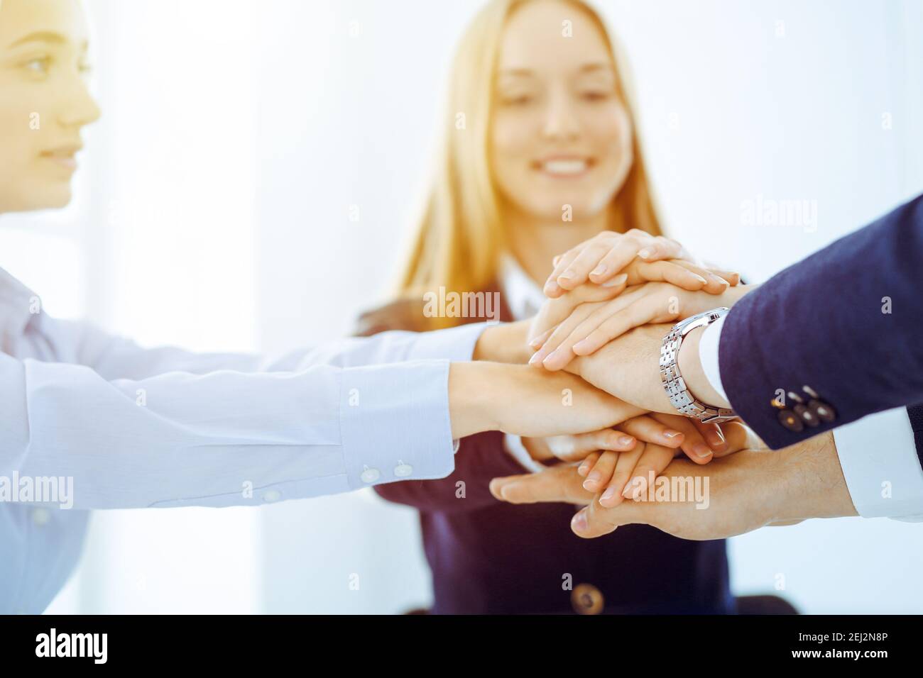 Business team showing unity with their hands together in sunny office ...