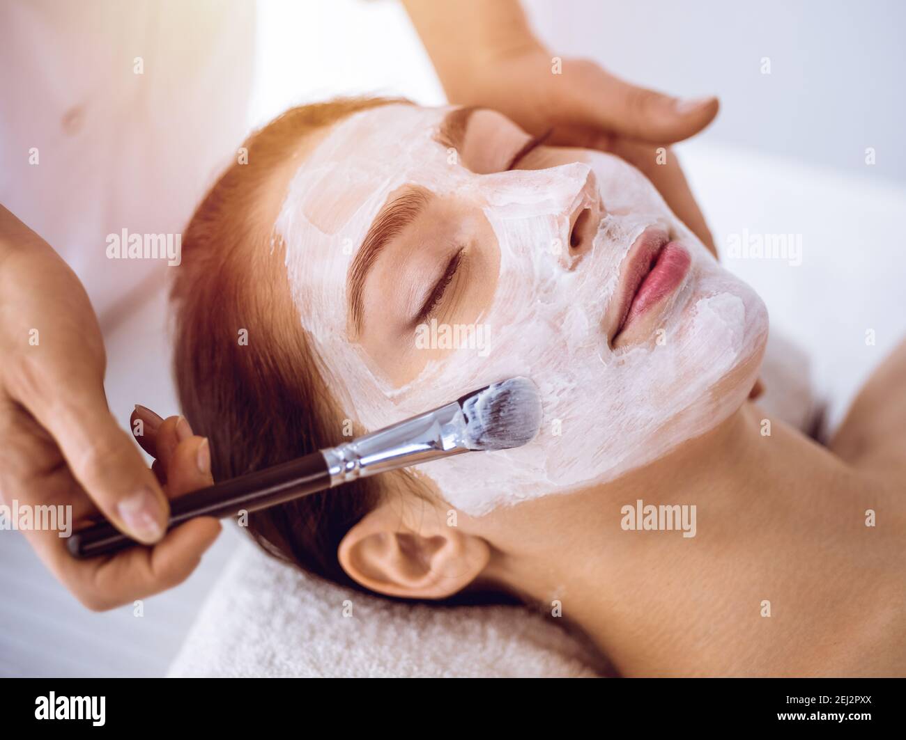 Beautiful brunette woman enjoying applying cosmetic mask with closed ...