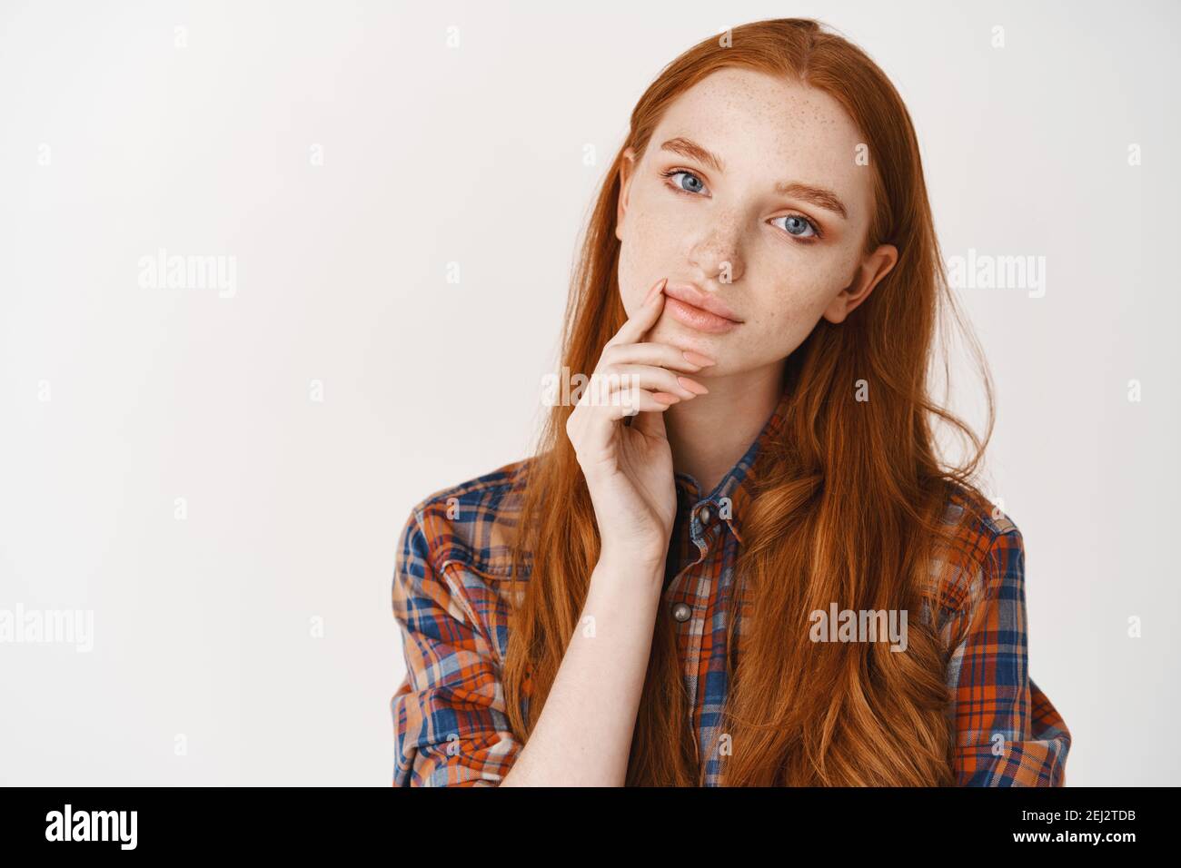 Young thoughtful ginger girl in shirt, without makeup, looking at ...