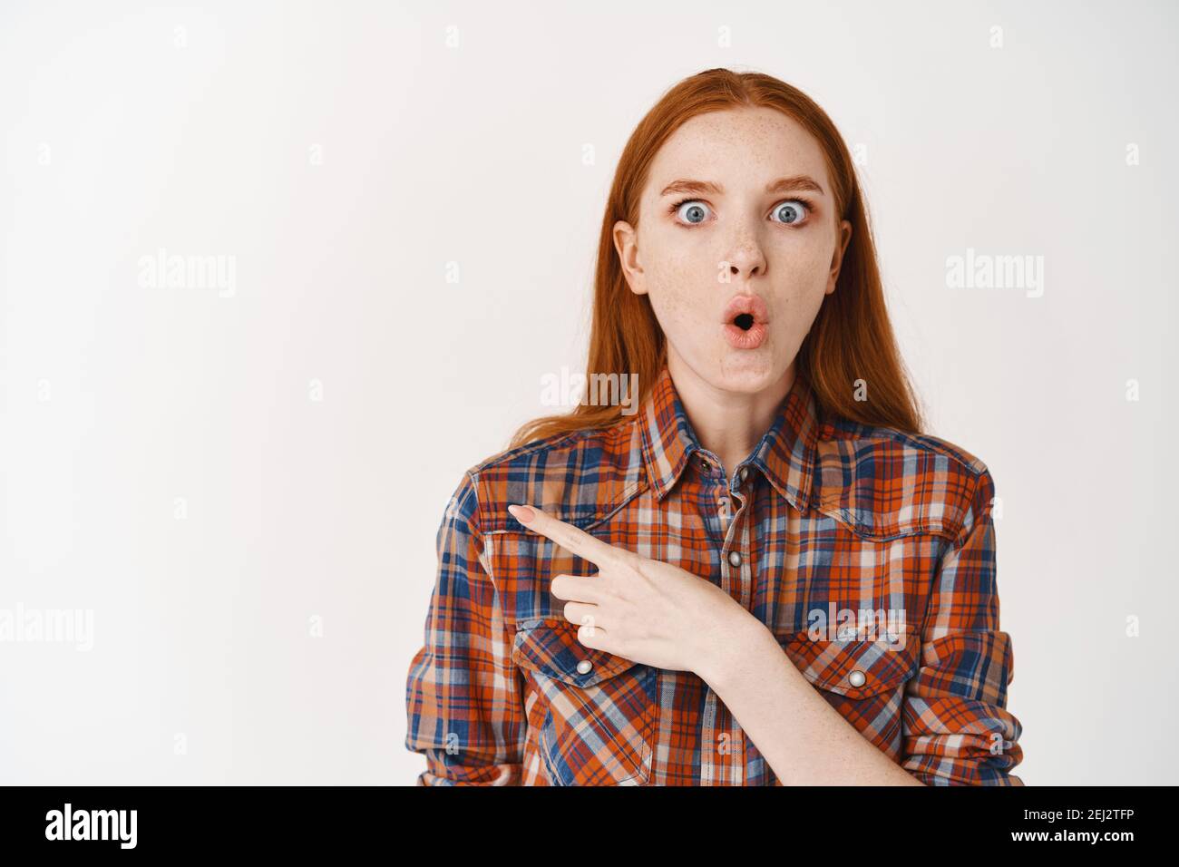 Impressed Redhead Girl Pointing Finger Left Showing Advertisement And