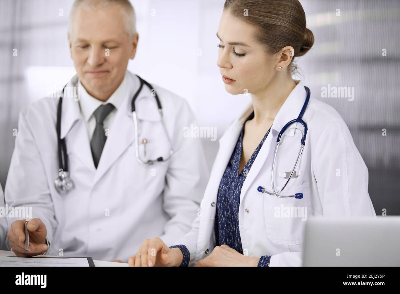 Doctors colleagues and elderly therapist discussing current disease ...