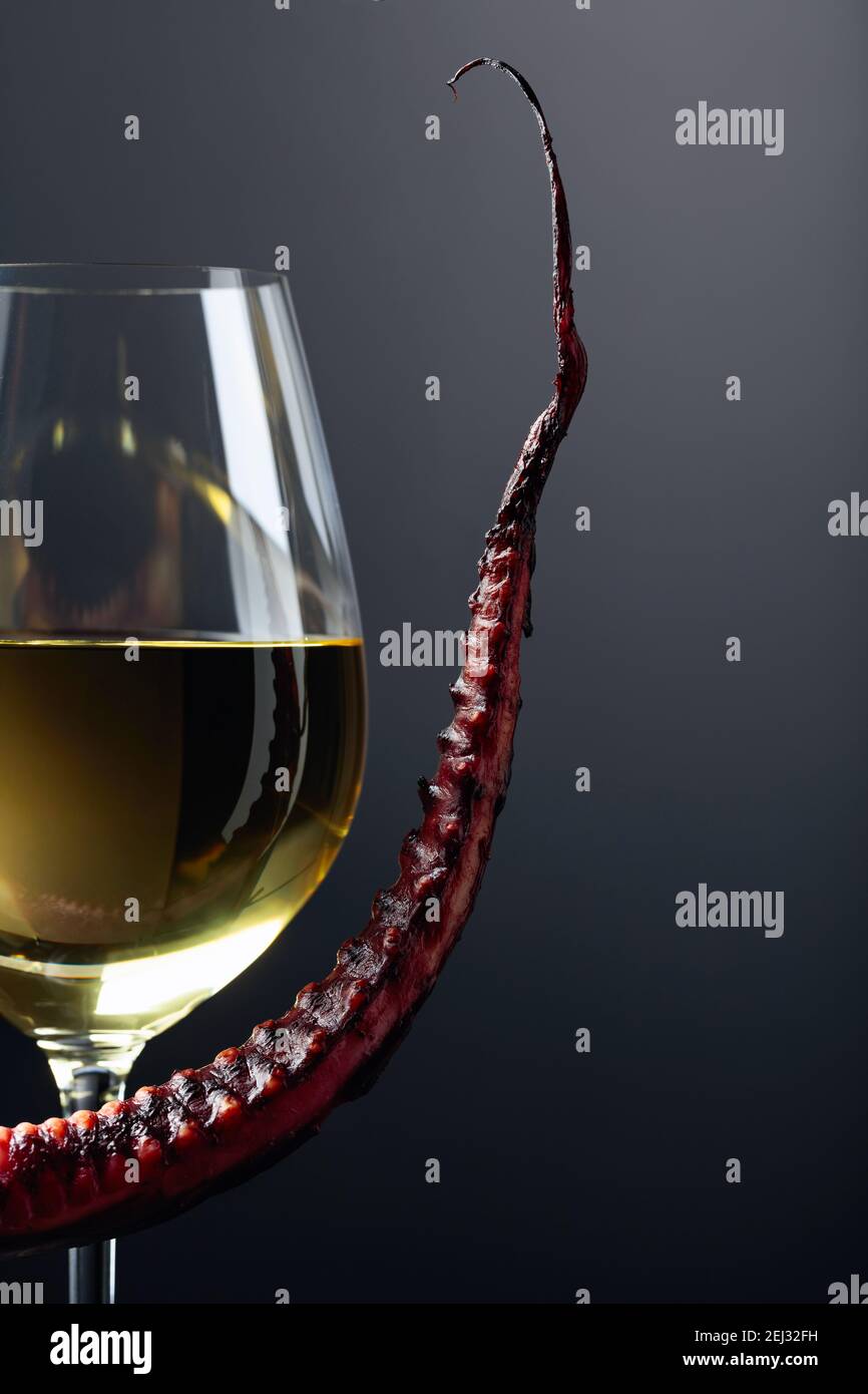 Grilled octopus and white wine glass on a black background. Copy space ...