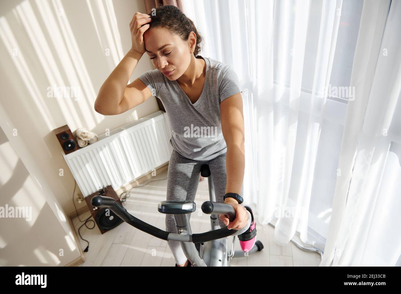 Young african woman feeling exhausted after training on a spin bike ...