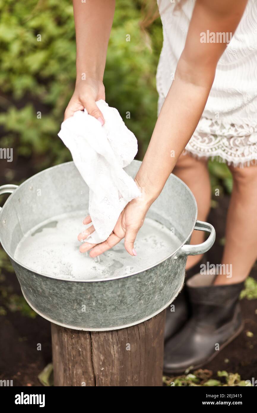 Woman washing clothes by hand in a tin basin. Retro style. Hand washing ...
