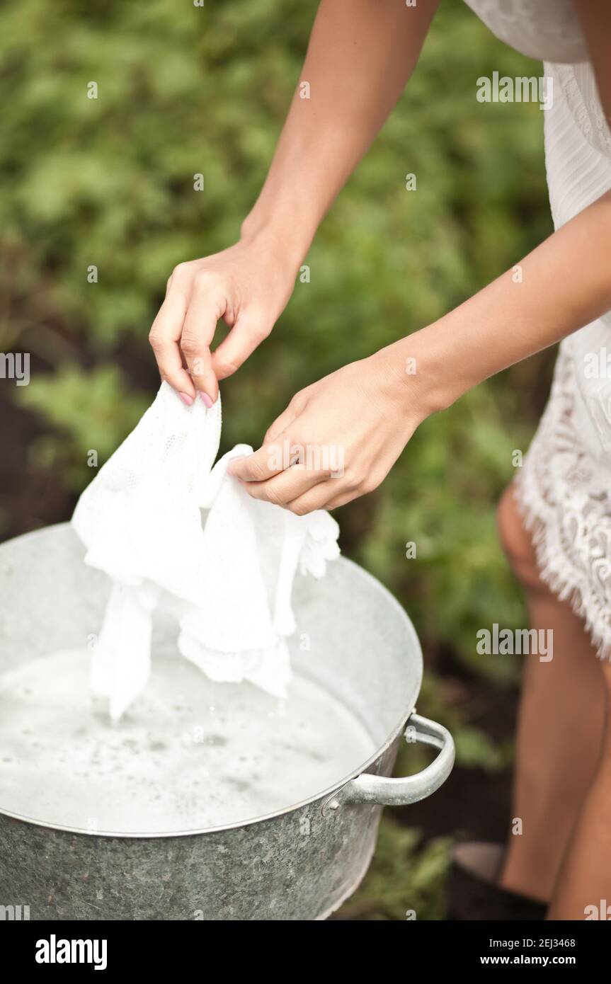 Woman washing clothes by hand in a tin basin. Retro style. Hand washing ...