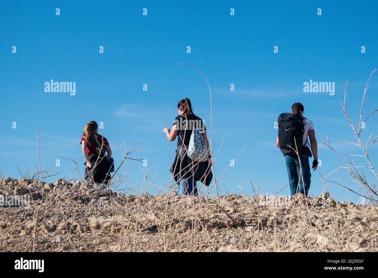 Three people on their backs hiking outdoors with a blue sky. Two women ...