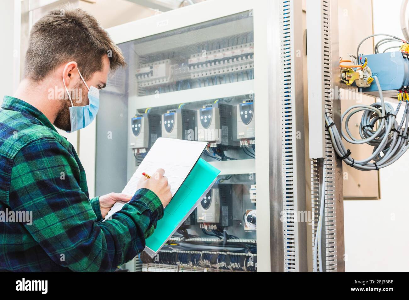 Young engineer taking notes on a notebook and doing the maintenance of ...